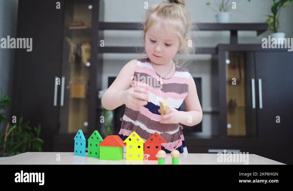 a cute little girl builds houses from a colorful wooden construction ...