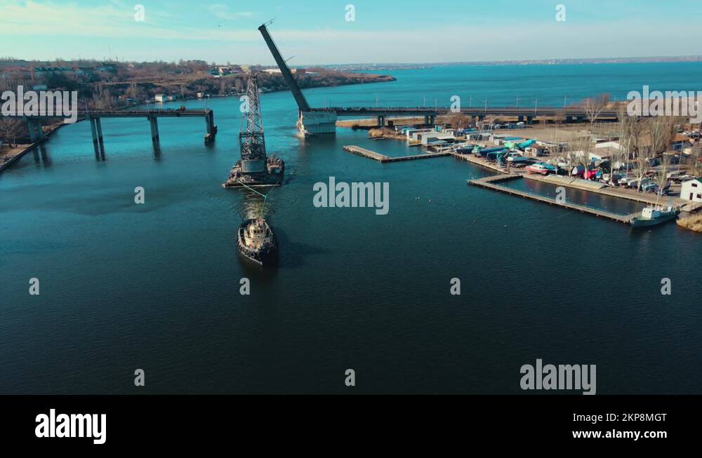 Tugboat pulling floating crane to shipyard slowly passing through ...