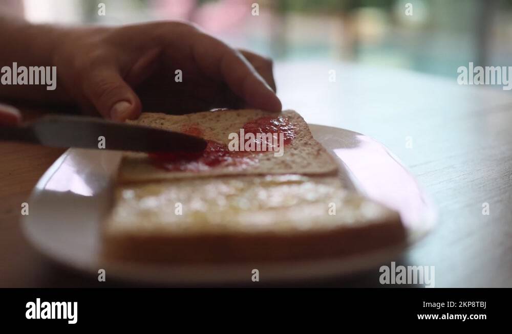 Spreading strawberry jam on bread. Knife smearing strawberry jam on ...