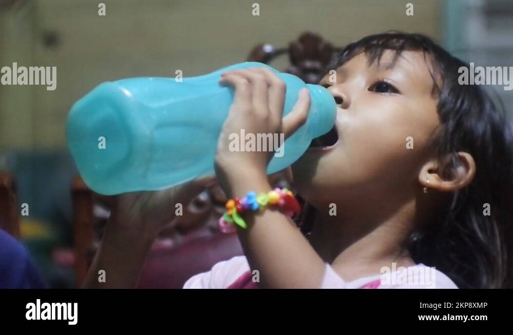 little girl drinking water from a bottle, blora, central java ...