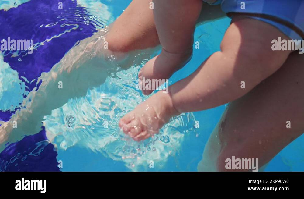 baby feet beating water of a swimming pool. legs of toddler splash in ...