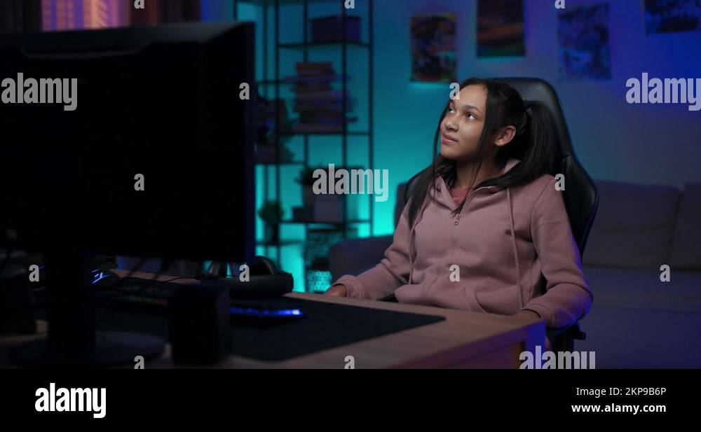 Young girl gamer sits in chair in front of computer has a break from ...