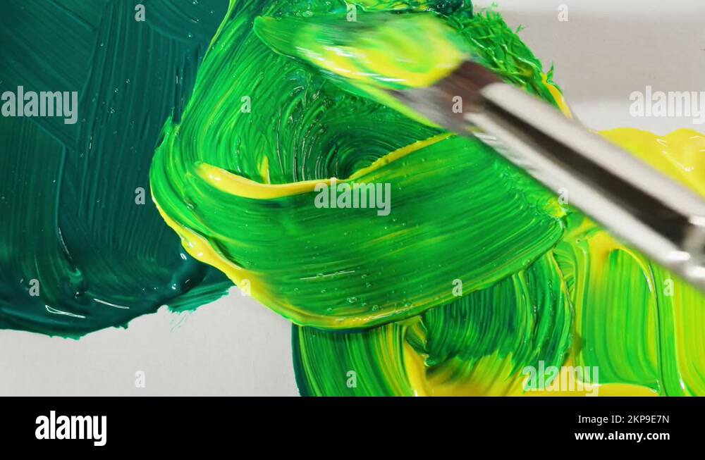 Mixing green and yellow paints close-up. Drawing on white paper top ...