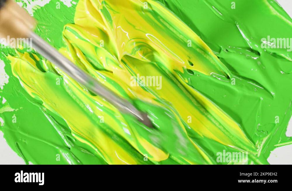 Mixing green and yellow paints close-up. Drawing on white paper top ...