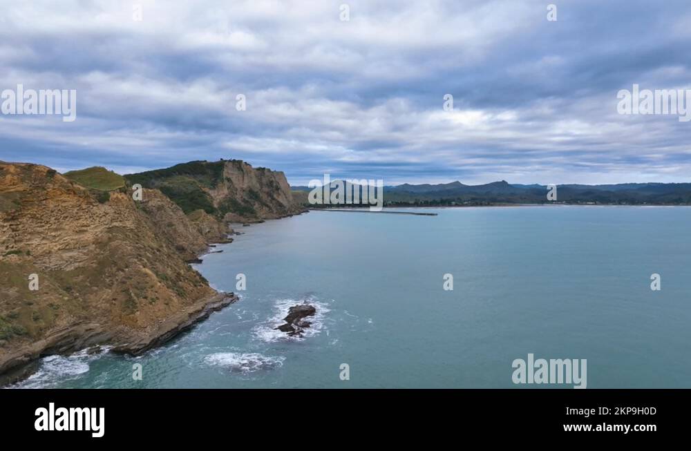 Rugged cliff at Tolaga Bay fly over small wind swept island - New ...