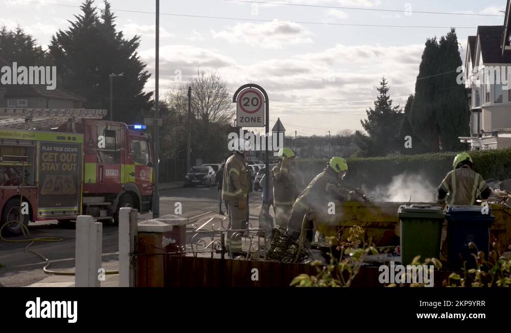Firefighters extinguishing a smouldering fire in a skip bin outside a ...