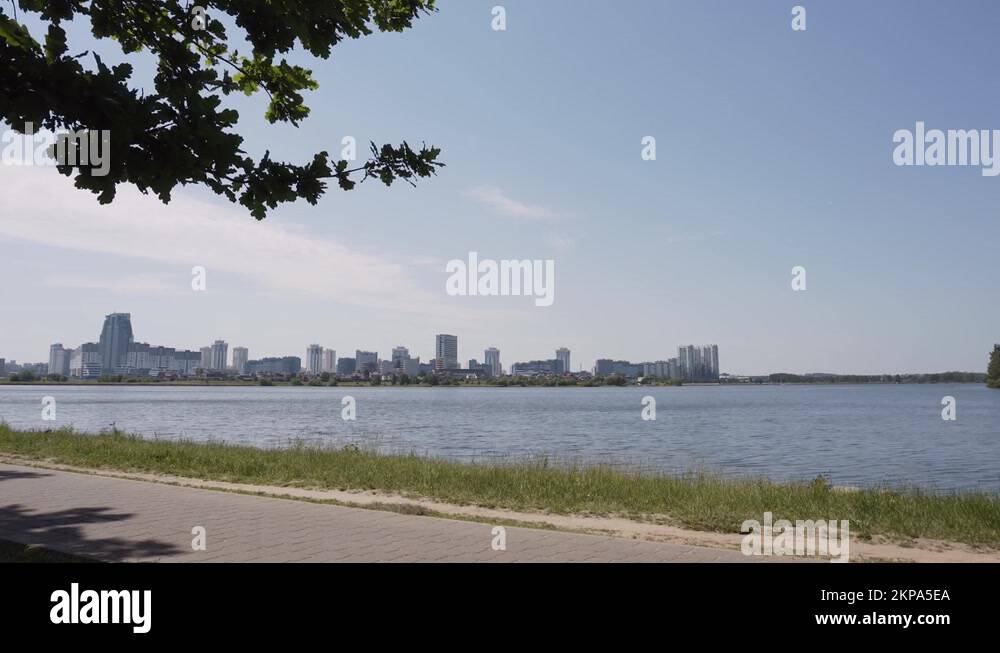 Lake embankment in park against backdrop of high-rise buildings with ...