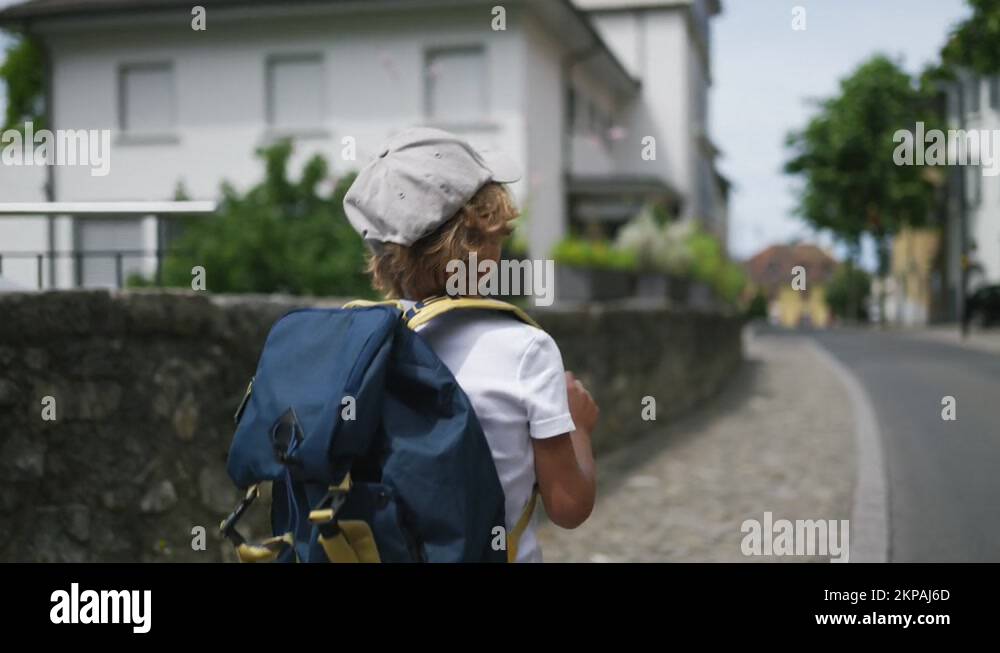 School boy walking to school carries backpack in European street Stock ...