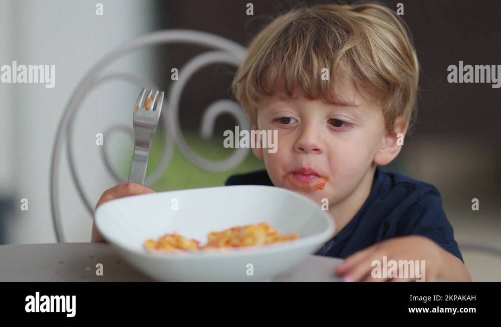 Little boy sitting at lunch tabel holding fork eating pasta Stock Video ...