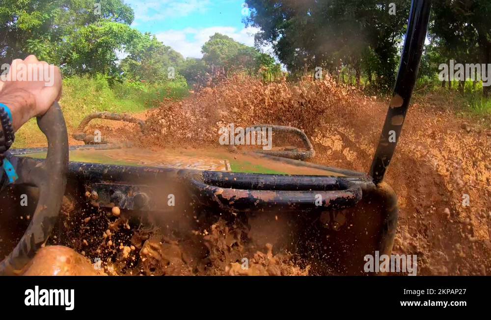 Passenger view from off-road buggy driving through mud with big splash ...