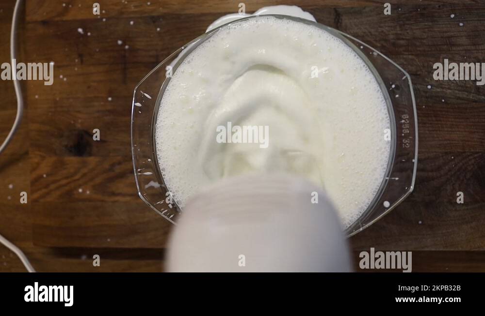 Whipping cream with an electric mixer. Mixing cream milk in bowl Stock ...