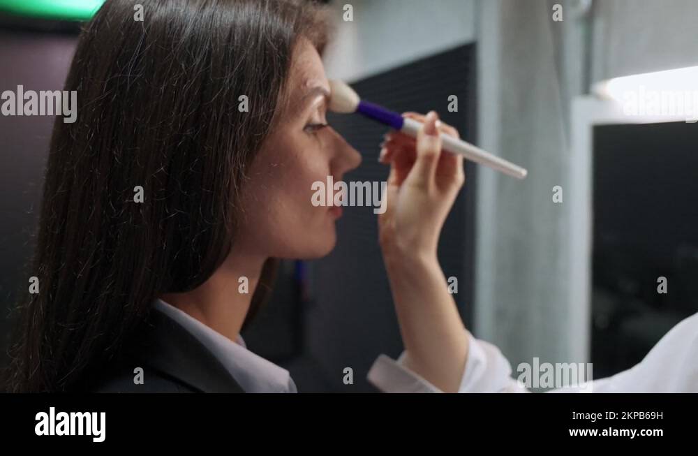 Handheld, female makeup artist make a makes up a TV presenter before ...