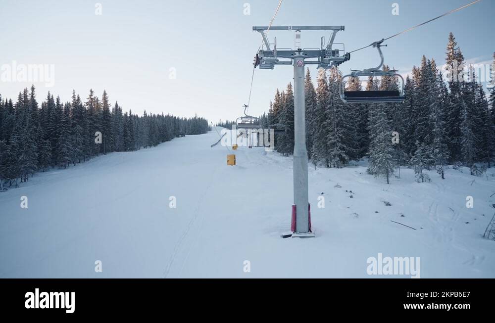 4K ski lift going uphill over the ski slope on a cold morning with blue ...