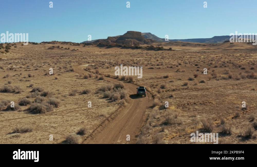 Aerial tracking car on remote dirt road in open desert with rock ...