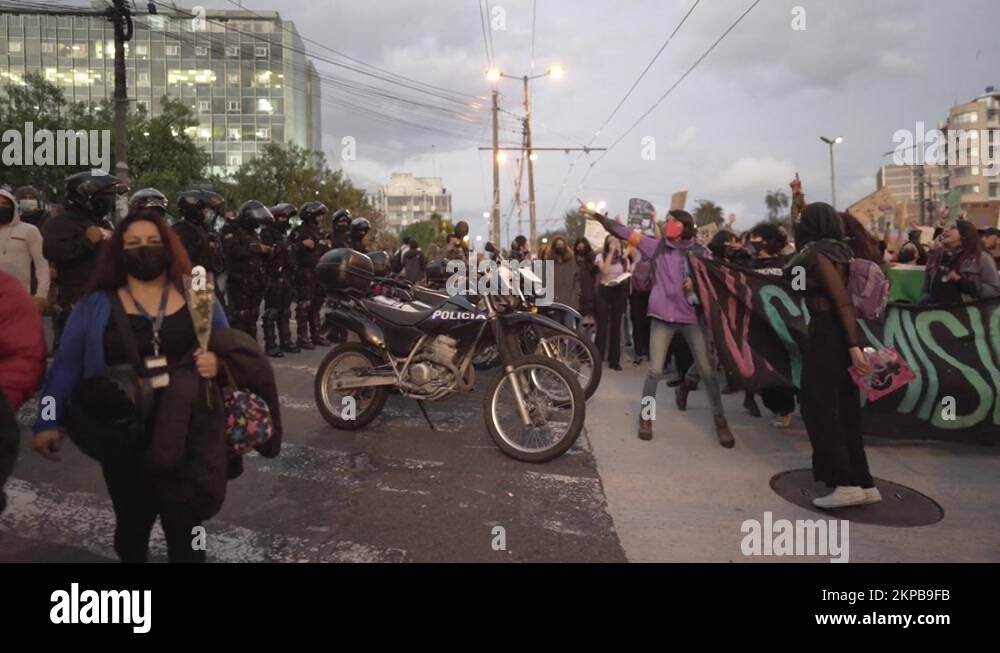 A group of women jump and sing to police officers while holding up ...