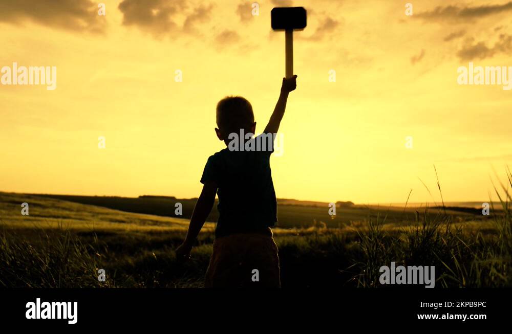 Silhouette child plays superhero from comics, child holds hammer in his ...
