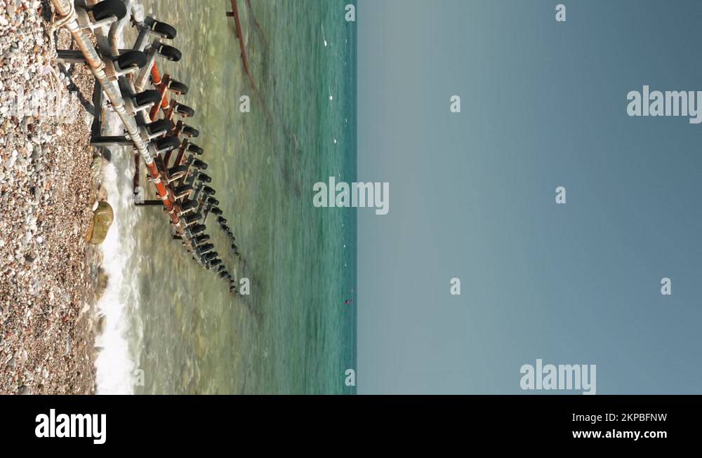 Pebble beach with sea water and roller rails for launching boat ...