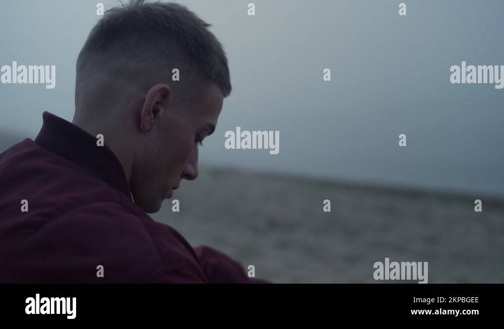 Sad man sitting sandy beach in morning. Young guy with upset face ...