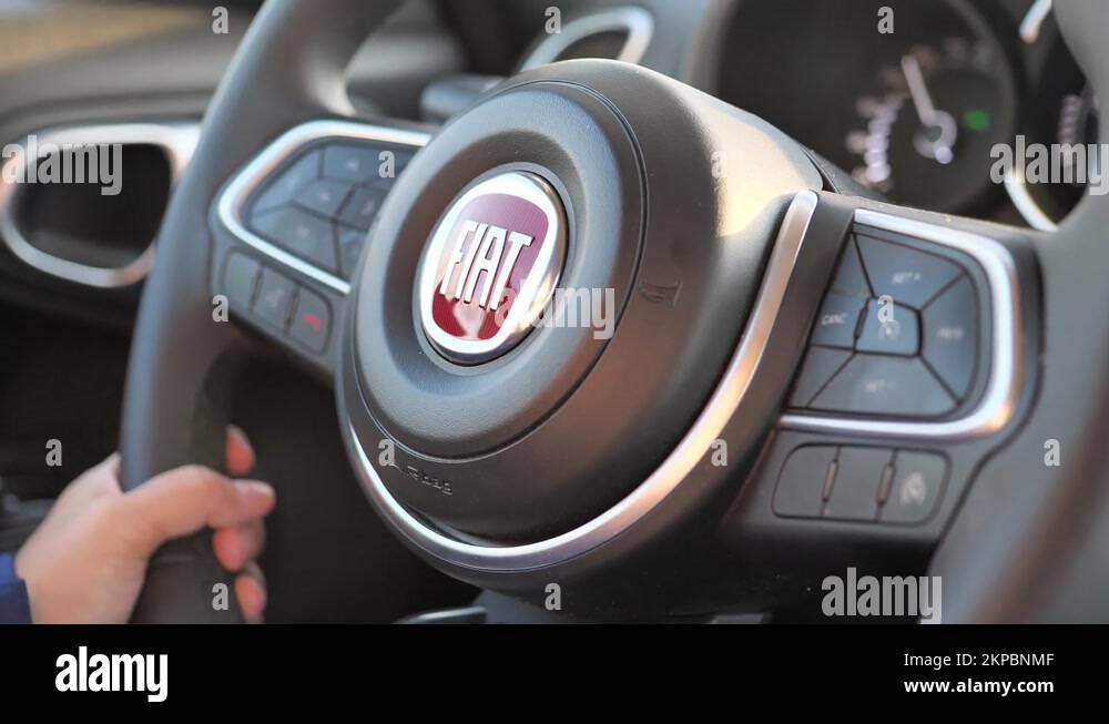 Driver driving Fiat 500X car with a detail on a steering wheel and the ...