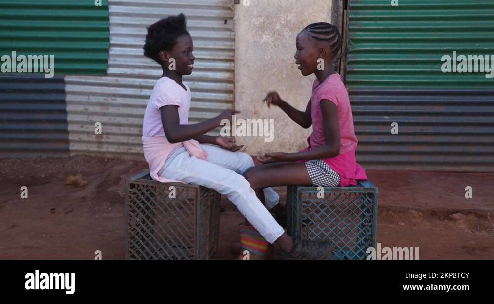 Poverty. Two cute Black African girls sitting playing a hand clapping ...