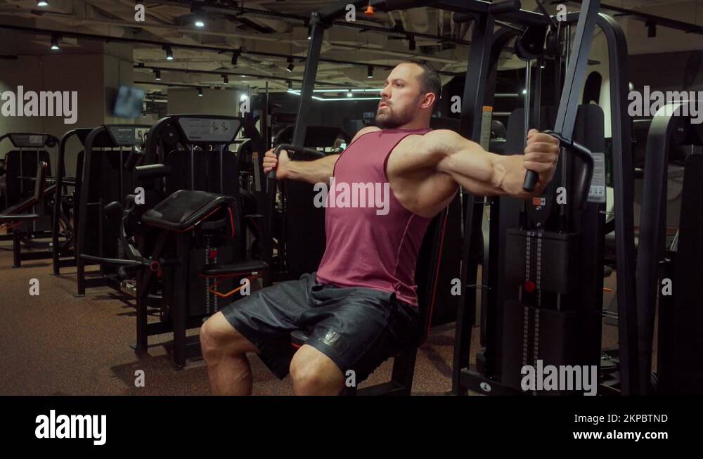 Bodybuilder performs an exercise on the chest muscles on a simulator in ...