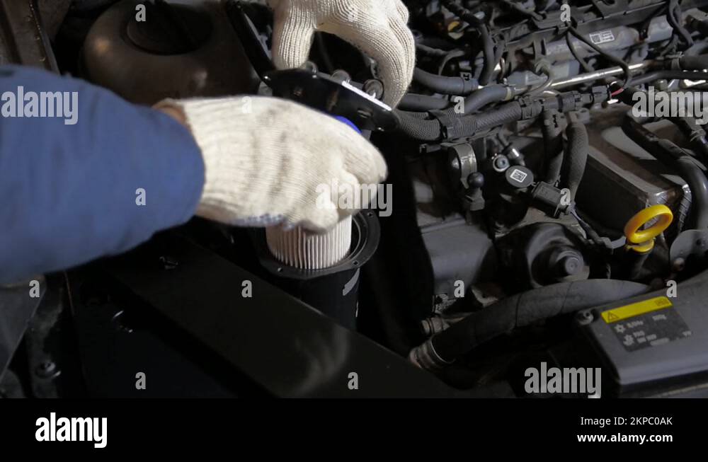 An automobile mechanic installs a new fuel filter in a car. Fuel filter ...