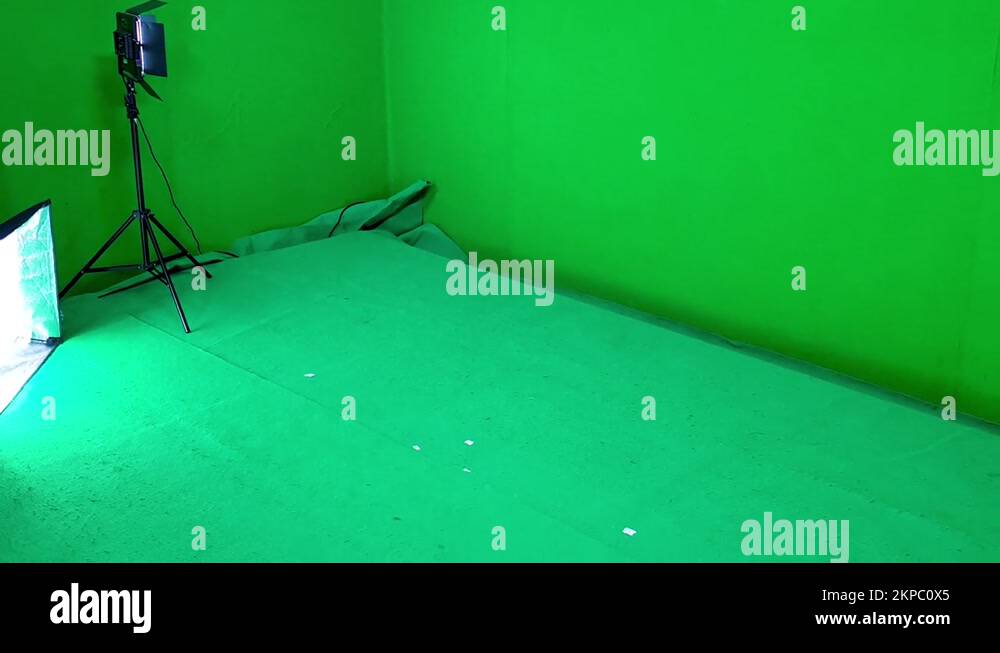A filming studio setup with green screen on walls and floor, lighting ...