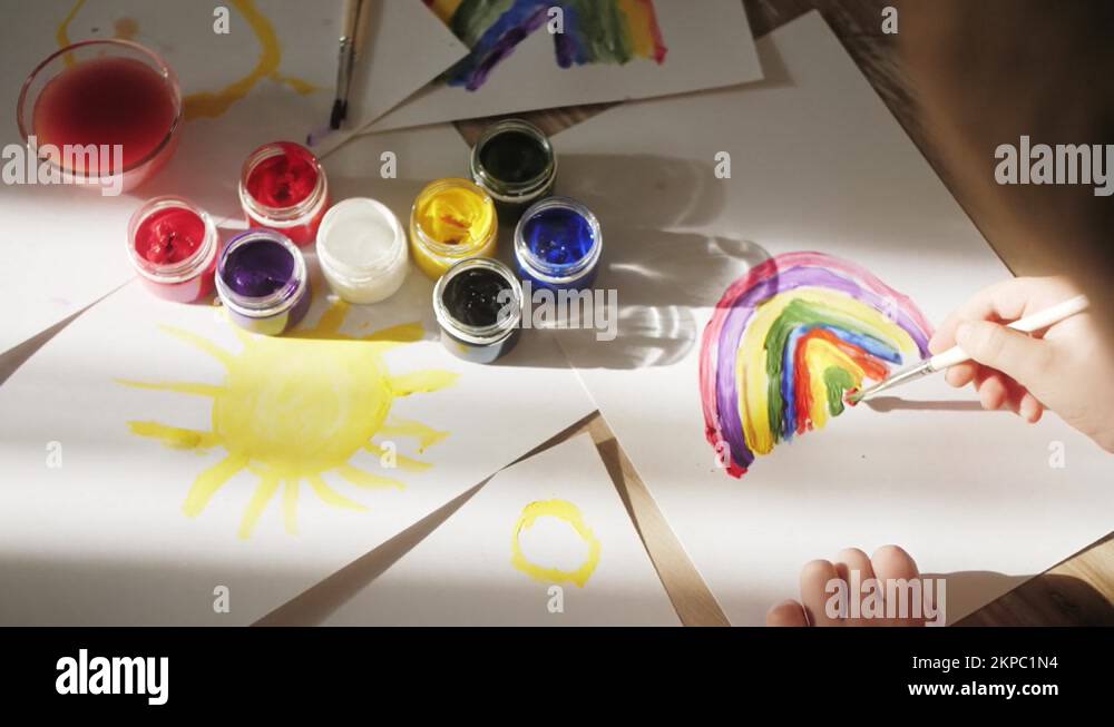 Child paints a rainbow. The rainbow is drawn by a close-up of children ...