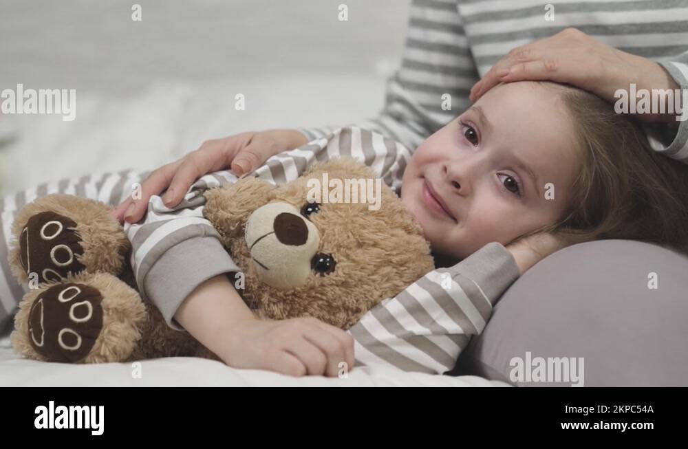 little child kid falls asleep mom lap hugging teddy bear. happy girl ...