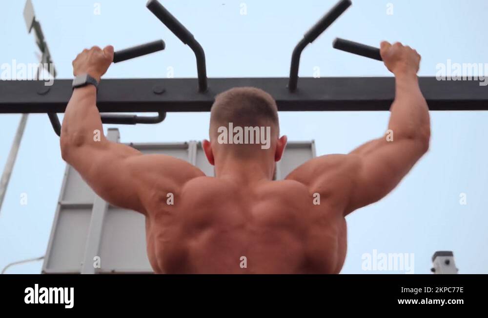 Athletic Man Pumps Up Muscles Doing Pull-Ups Open Sports Ground with ...