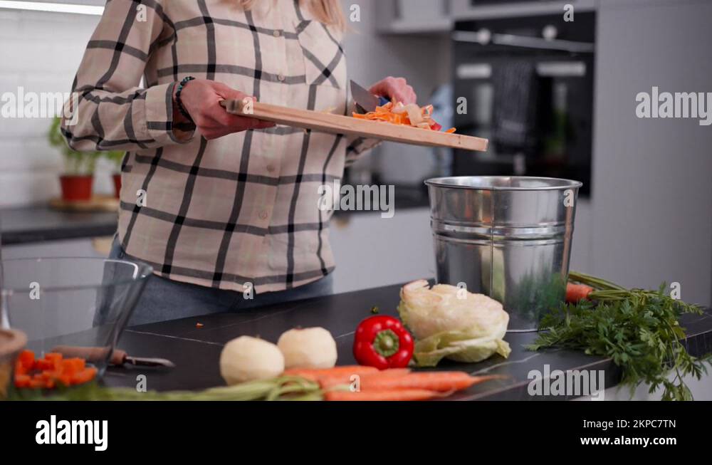 Woman throwing vegetable cuttings in a compost bucket in kitchen Stock ...