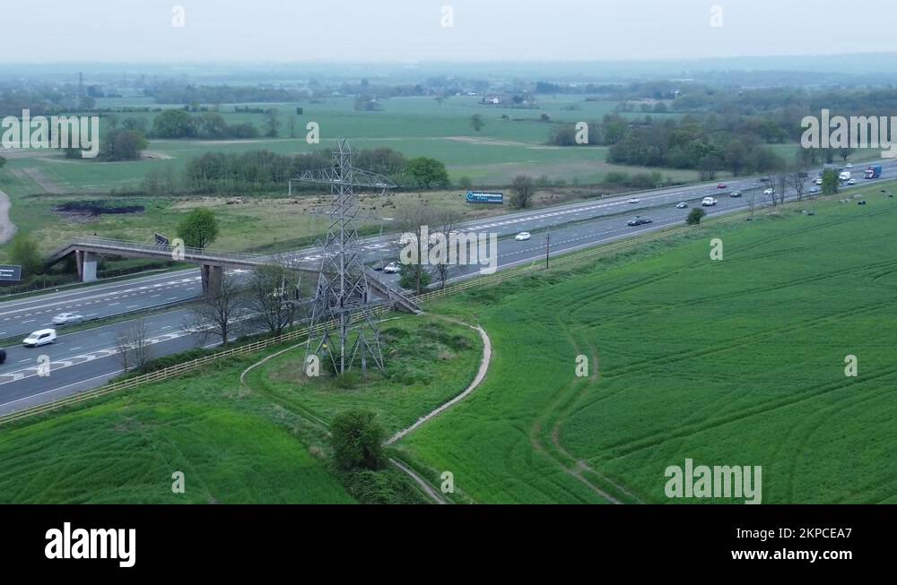 Vehicles on M62 motorway passing pylon tower on countryside farmland ...