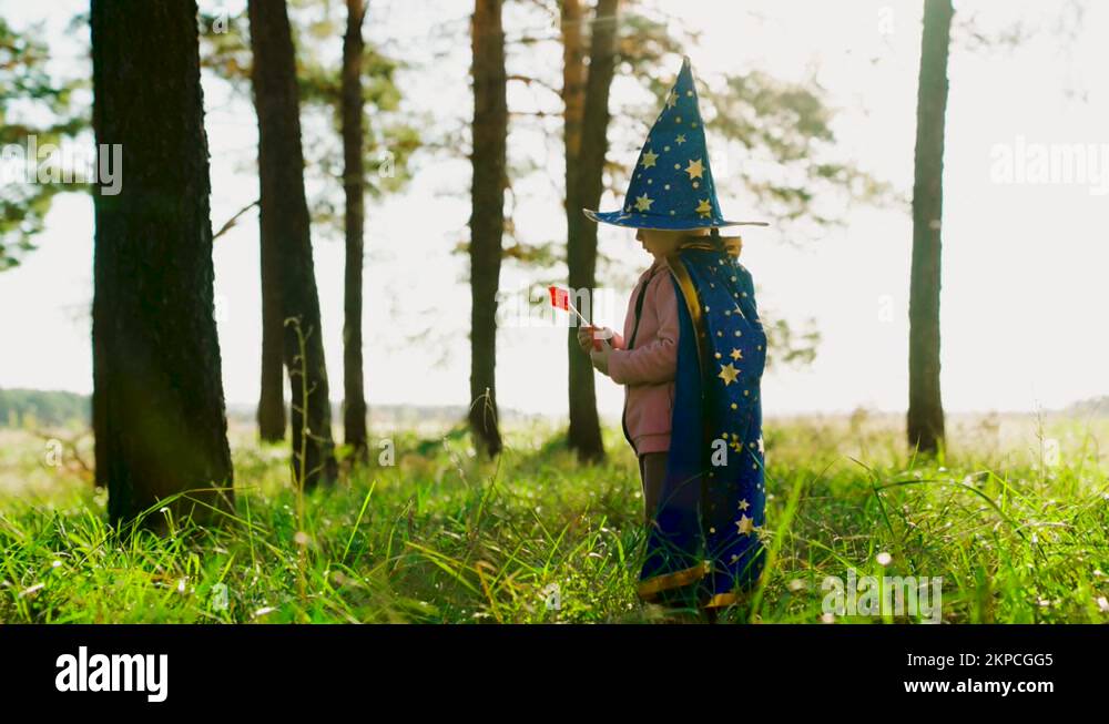 Girl, child plays in wizard costume, holds toy with a magic wand in ...