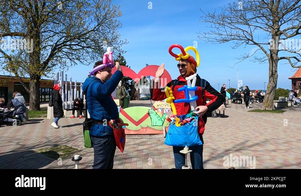 Two guys at a street food fair in balloon crafts high five each other ...