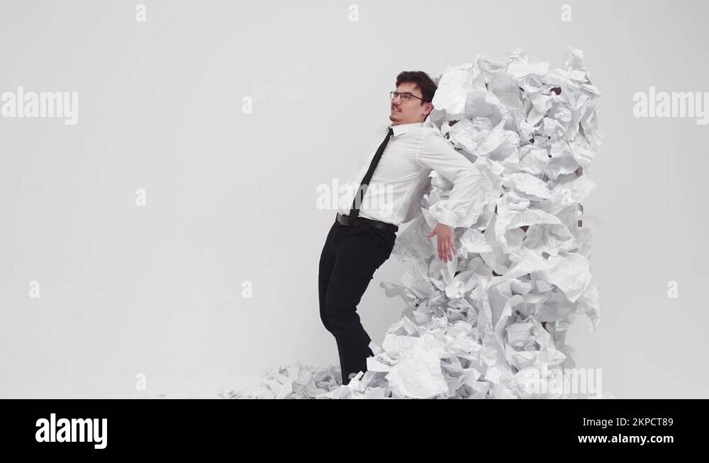 Male office worker tries to move mountain of crumpled documents, side ...