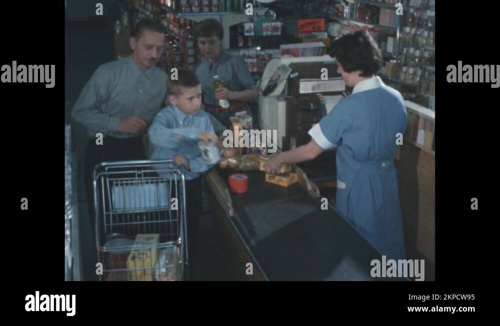 1960s: Man, woman and two children in grocery store place items on ...