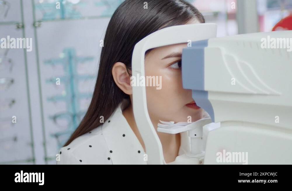 Young female customer being examined visual test using autorefractor by ...