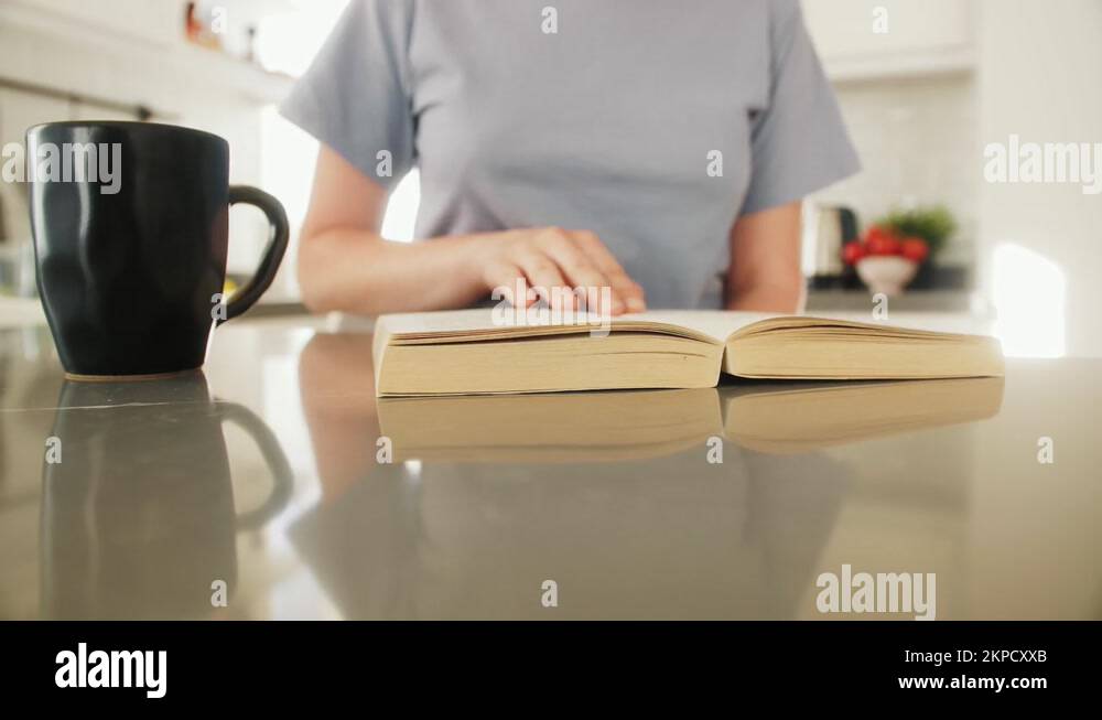 Woman turning pages of a book and moves her fingers along the page ...