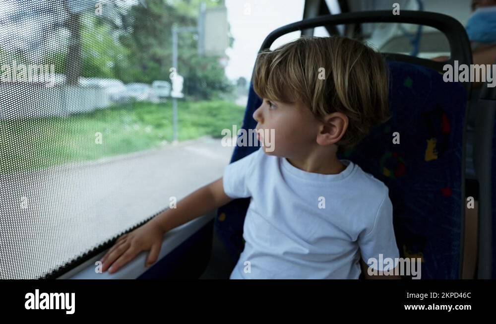 Passenger child sitting inside bus seat looking out through window ...