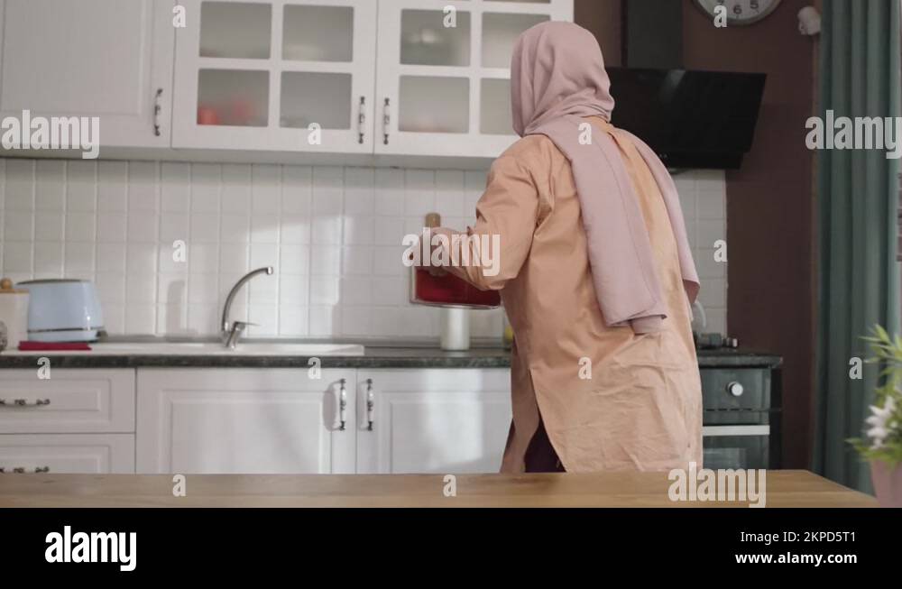 A young woman in a turban takes the pot from the table to light the ...