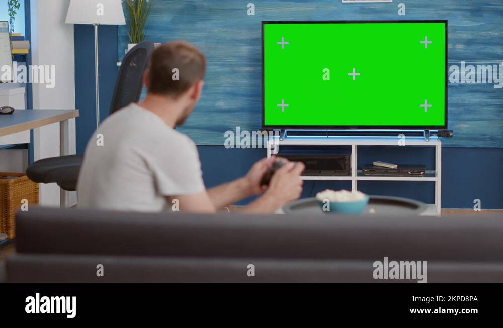 Man holding wireless controller playing console video game on green ...