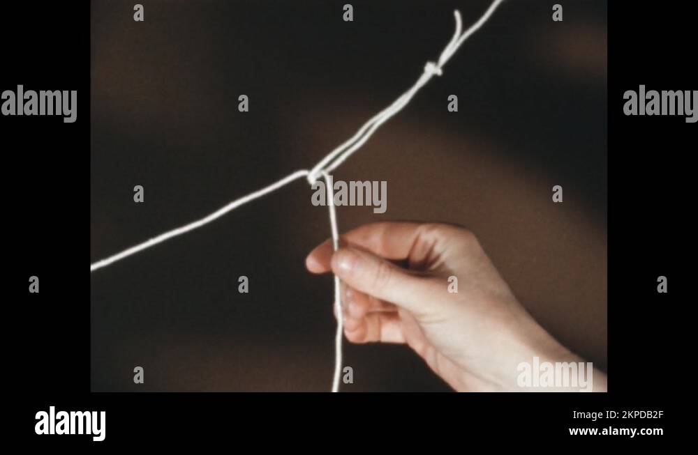 1960s: A hand follows a suspended string tied to one end of a glass ...