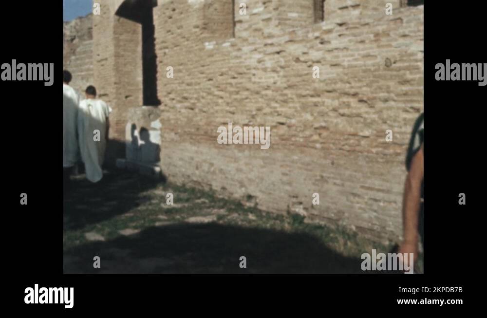 100 BC: Men wear togas, walk by building. Model of buildings ...