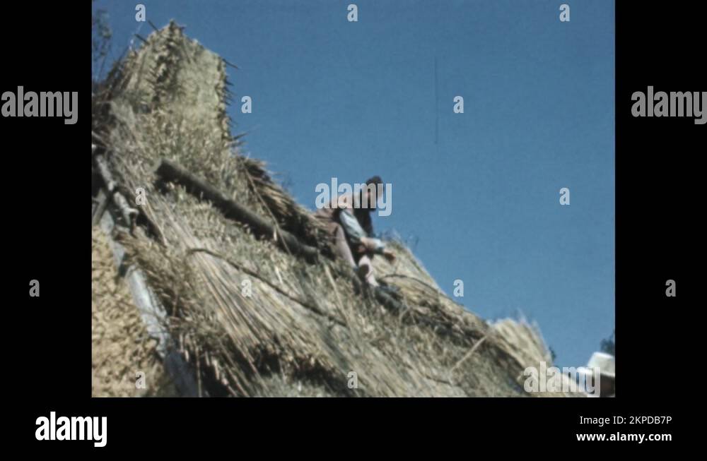 100 BC: Man throws bale of straw to man standing on thatched roof. Man ...