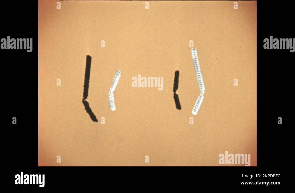 1960s: Different colored pipe cleaners on light table. Man and woman ...