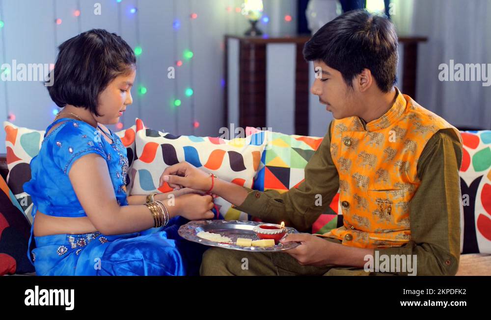 A cute little girl in traditional clothes tying a Rakhi on her elder ...