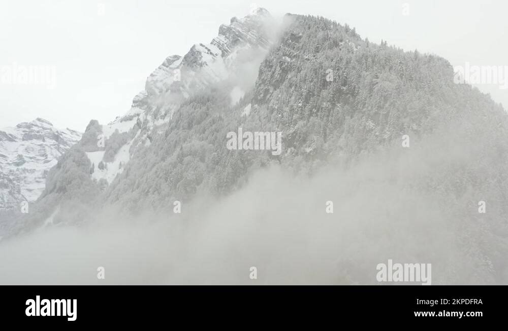Slow flight into misty and snowy rugged mountains in the alps Stock ...