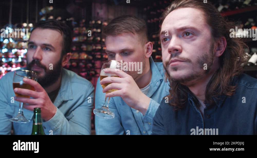 Caucasian handsome guys drinking beer in pub at night, talking and ...