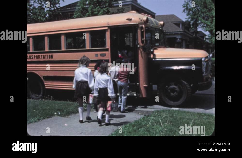 1970s: Children wait at bus stop, school bus pulls up, children board ...