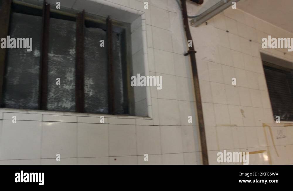 A scary prison cell with bars on the windows. The creepy room has tiled ...